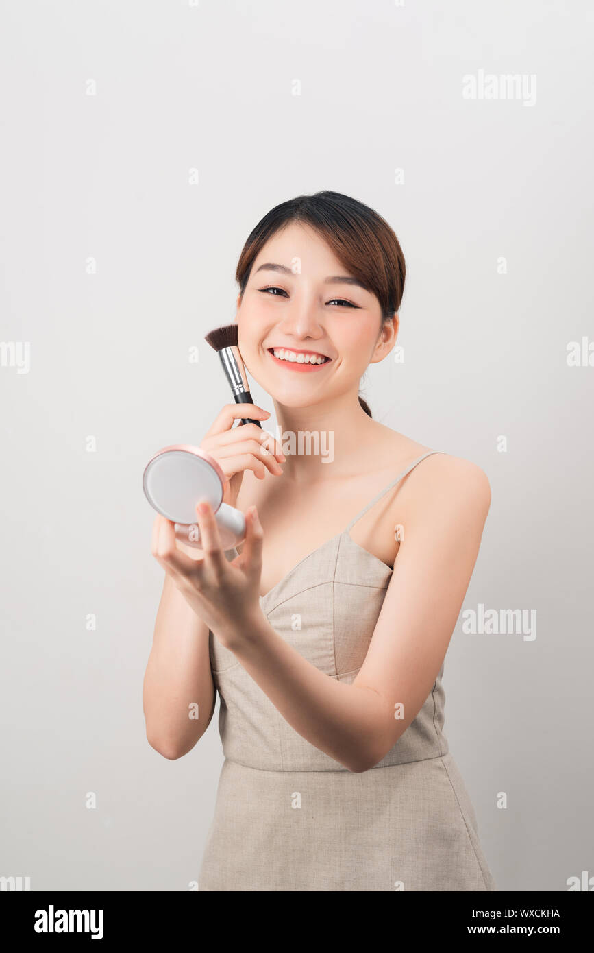 Portrait of a young beautiful woman applying foundation with black ...