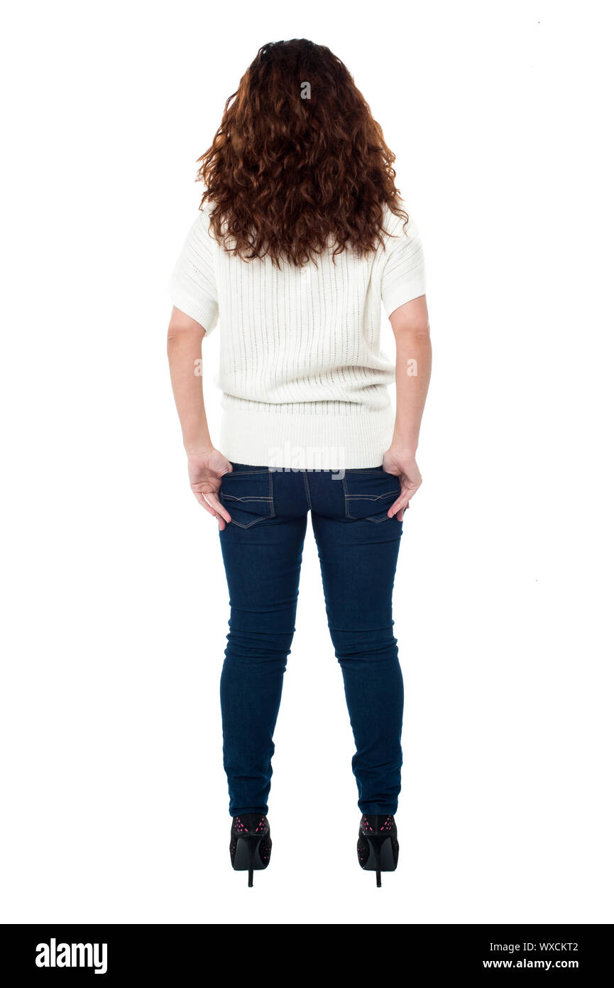Back pose of fashionable woman with a long curly hair facing the wall ...