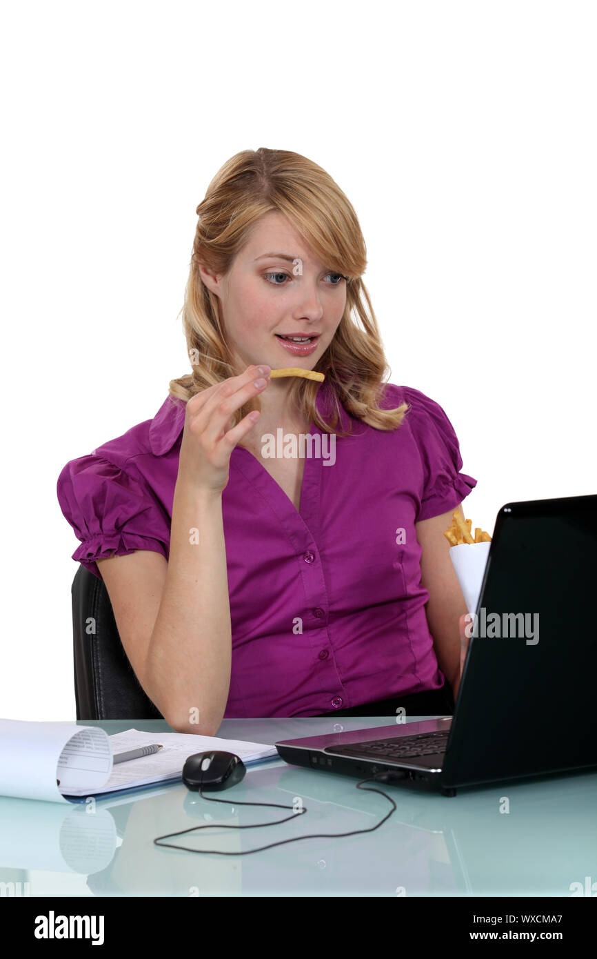 Employee eating French fries in front of her computer Stock Photo - Alamy