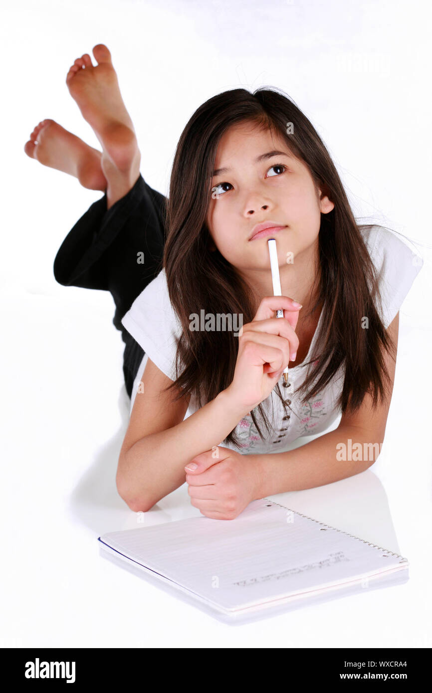 Child thinking while writing in notebook, lying on floor Stock Photo ...