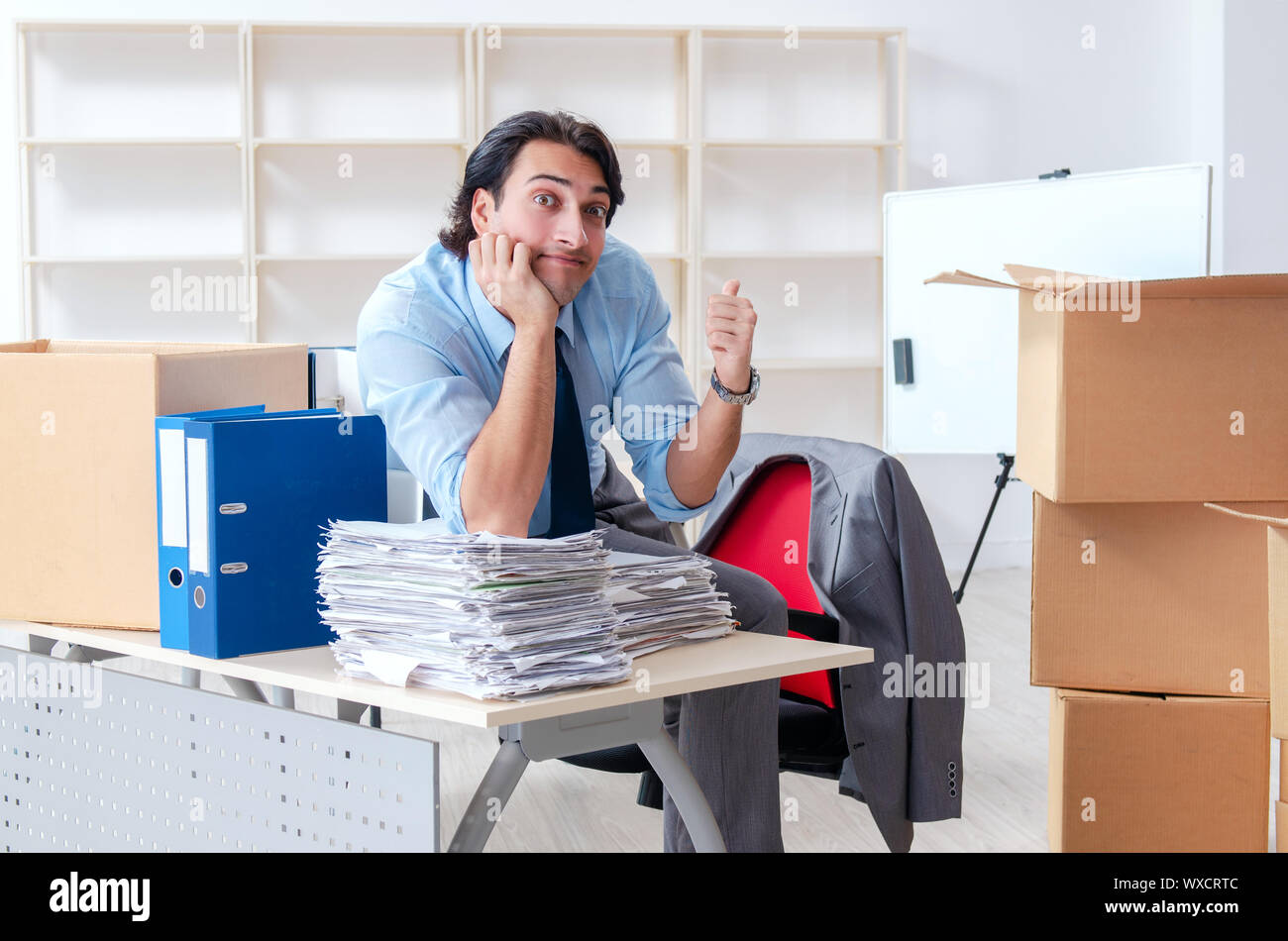 Young man employee with boxes in the office Stock Photo - Alamy