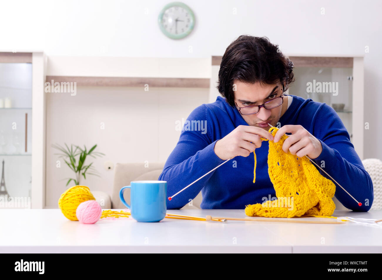 Young good looking man knitting at home Stock Photo - Alamy