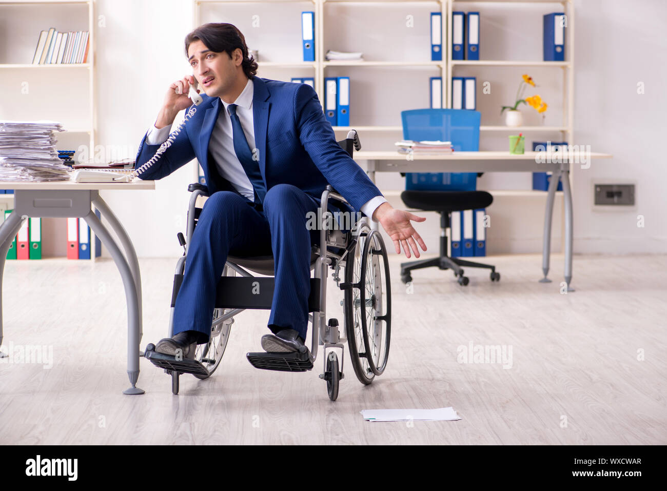 Young male employee in wheelchair working in the office Stock Photo - Alamy
