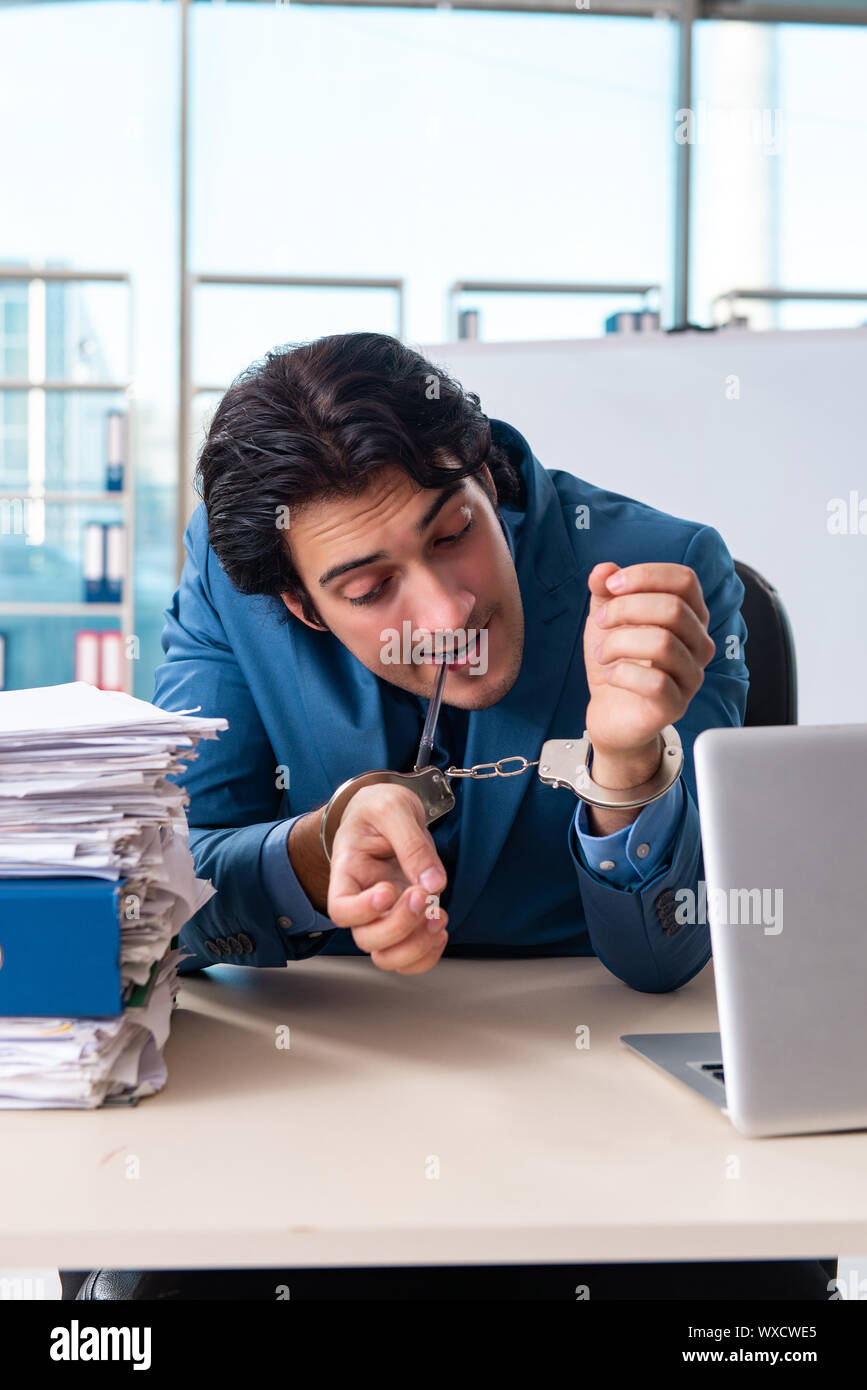 Chained male employee unhappy with excessive work Stock Photo - Alamy