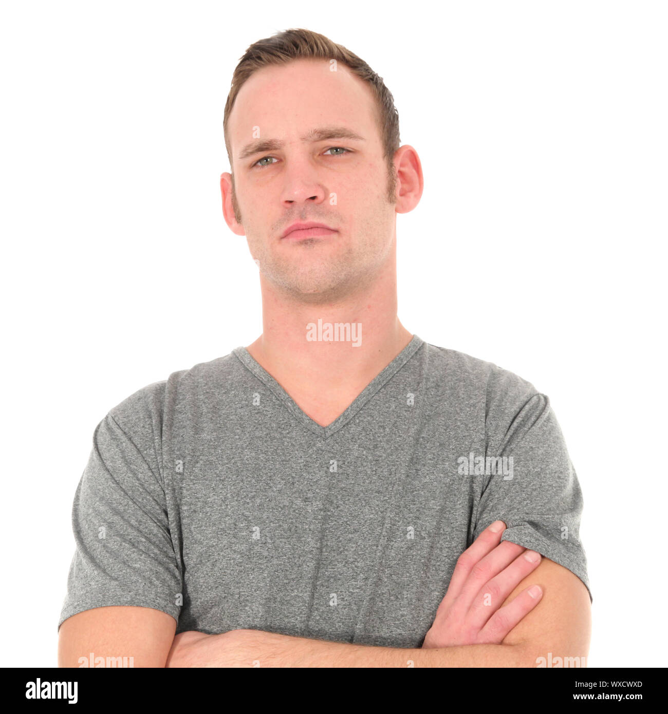 Unimpressed young man with a serious expression standing with his arms ...