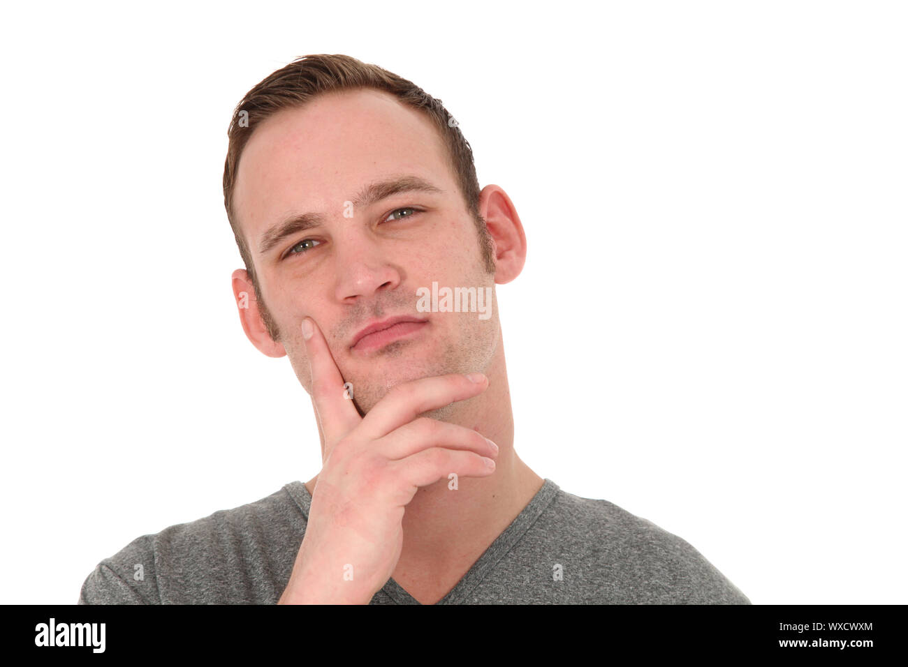 Pensive attractive young man standing thinking with his hand to his ...