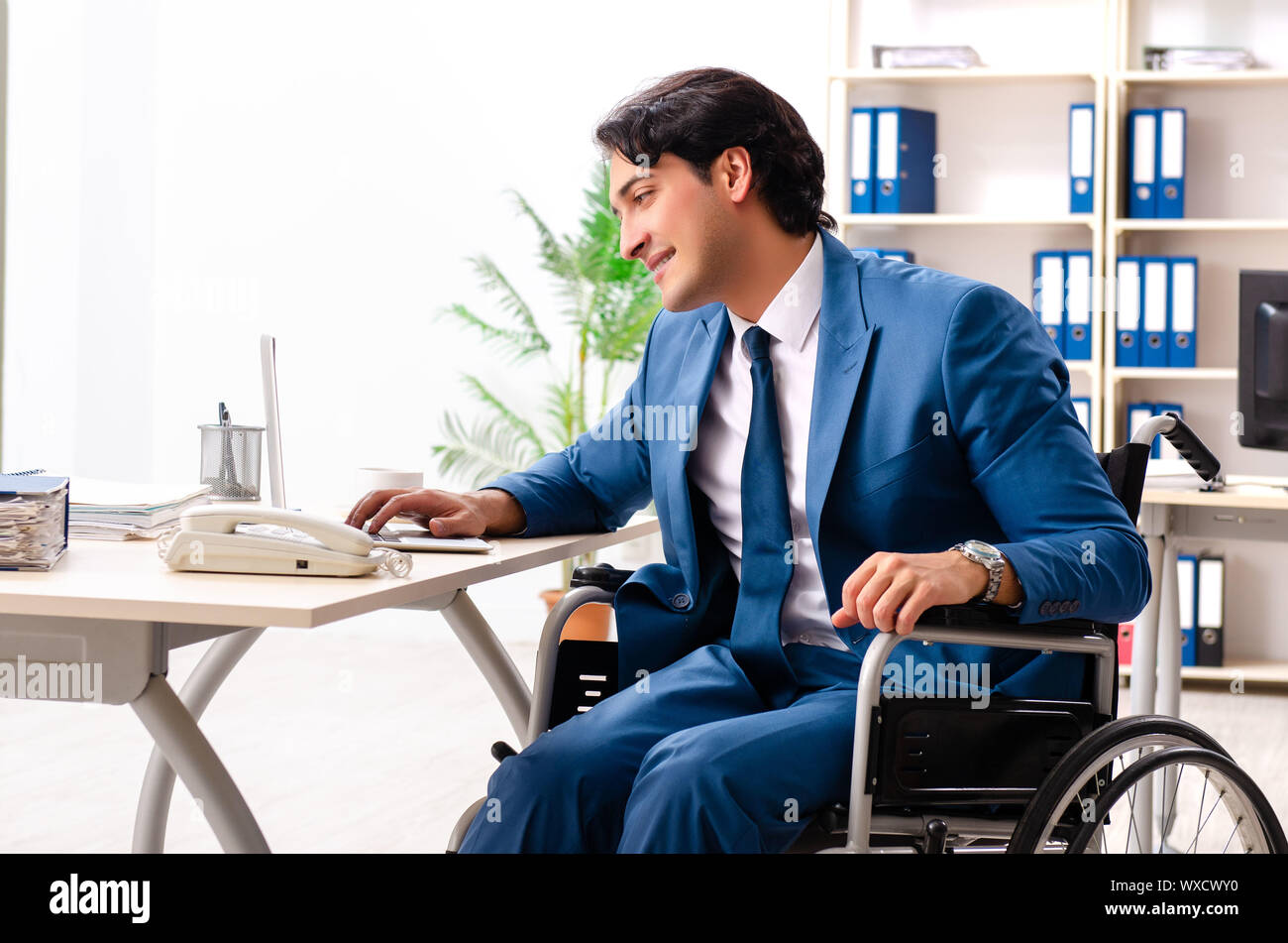 Male employee in wheelchair working at the office Stock Photo - Alamy
