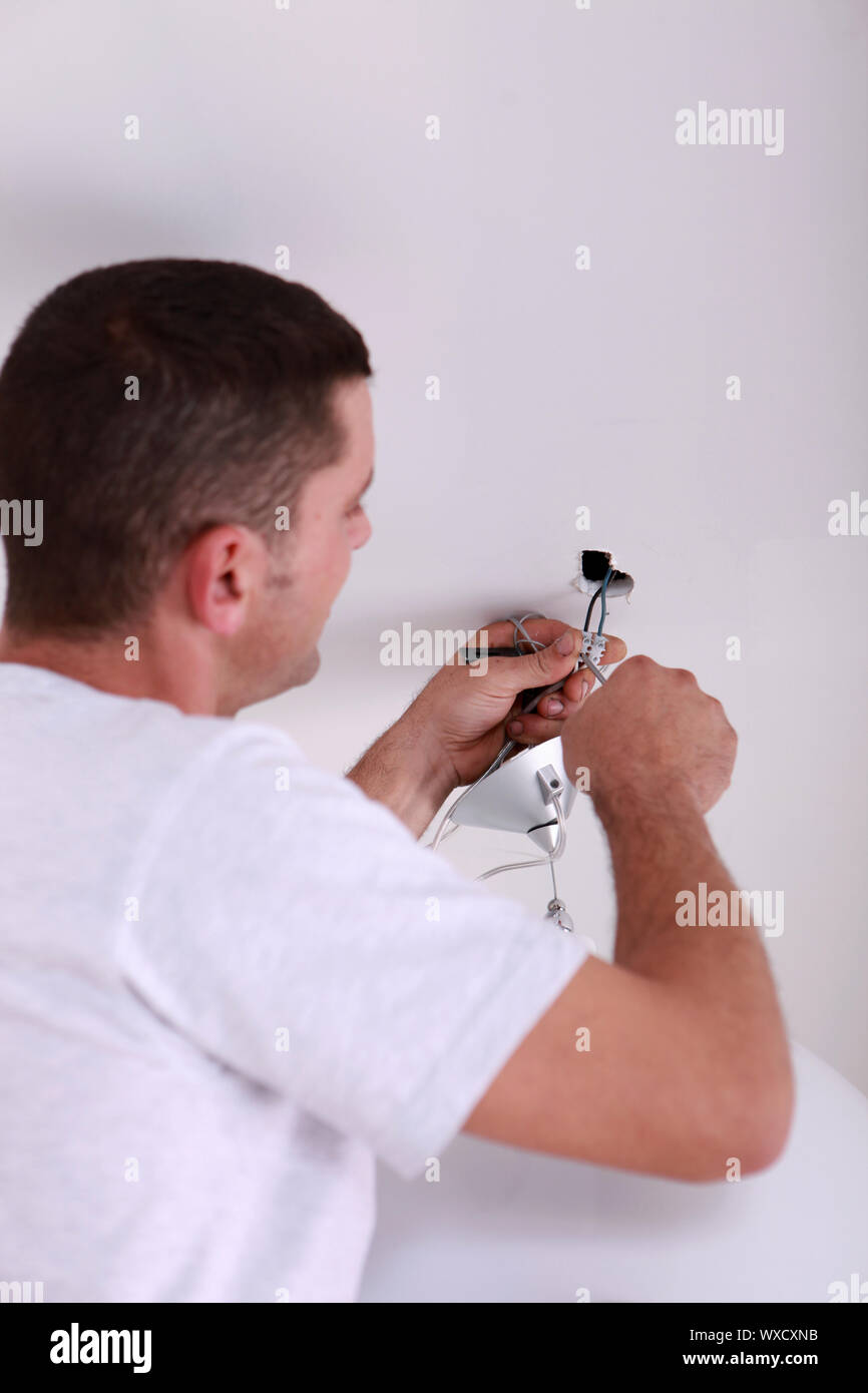 Man fixing ceiling light Stock Photo - Alamy