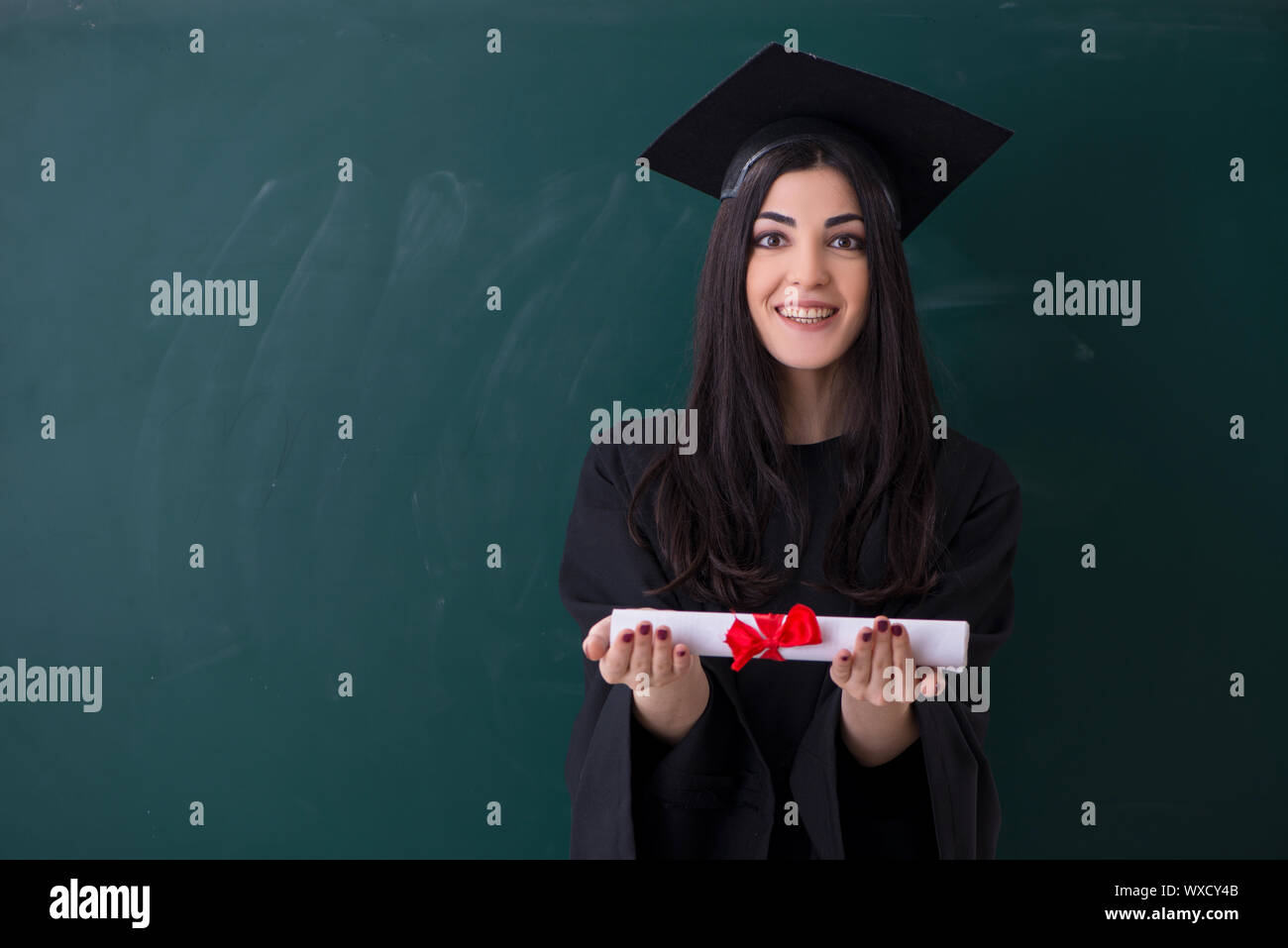 Female graduate student in front of green board Stock Photo - Alamy