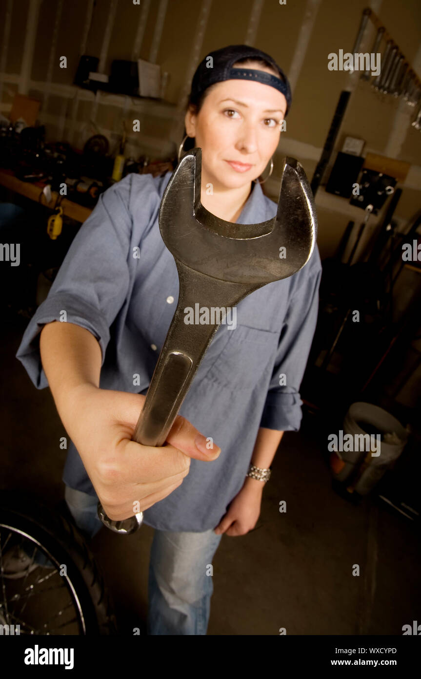 Hispanic woman in a garage with wrench Stock Photo - Alamy