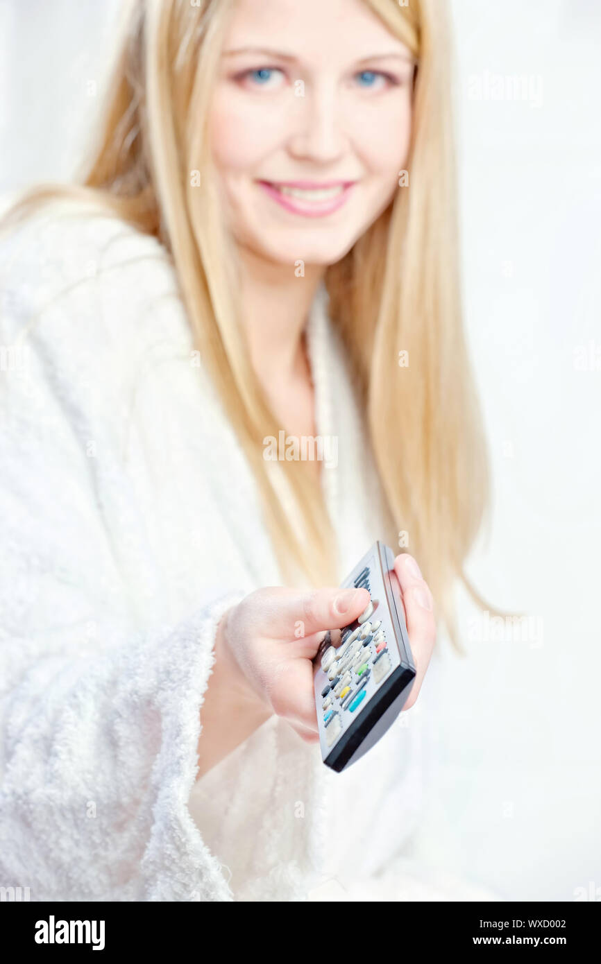 TV remote controller in hand of a pretty blond woman, focus on ...