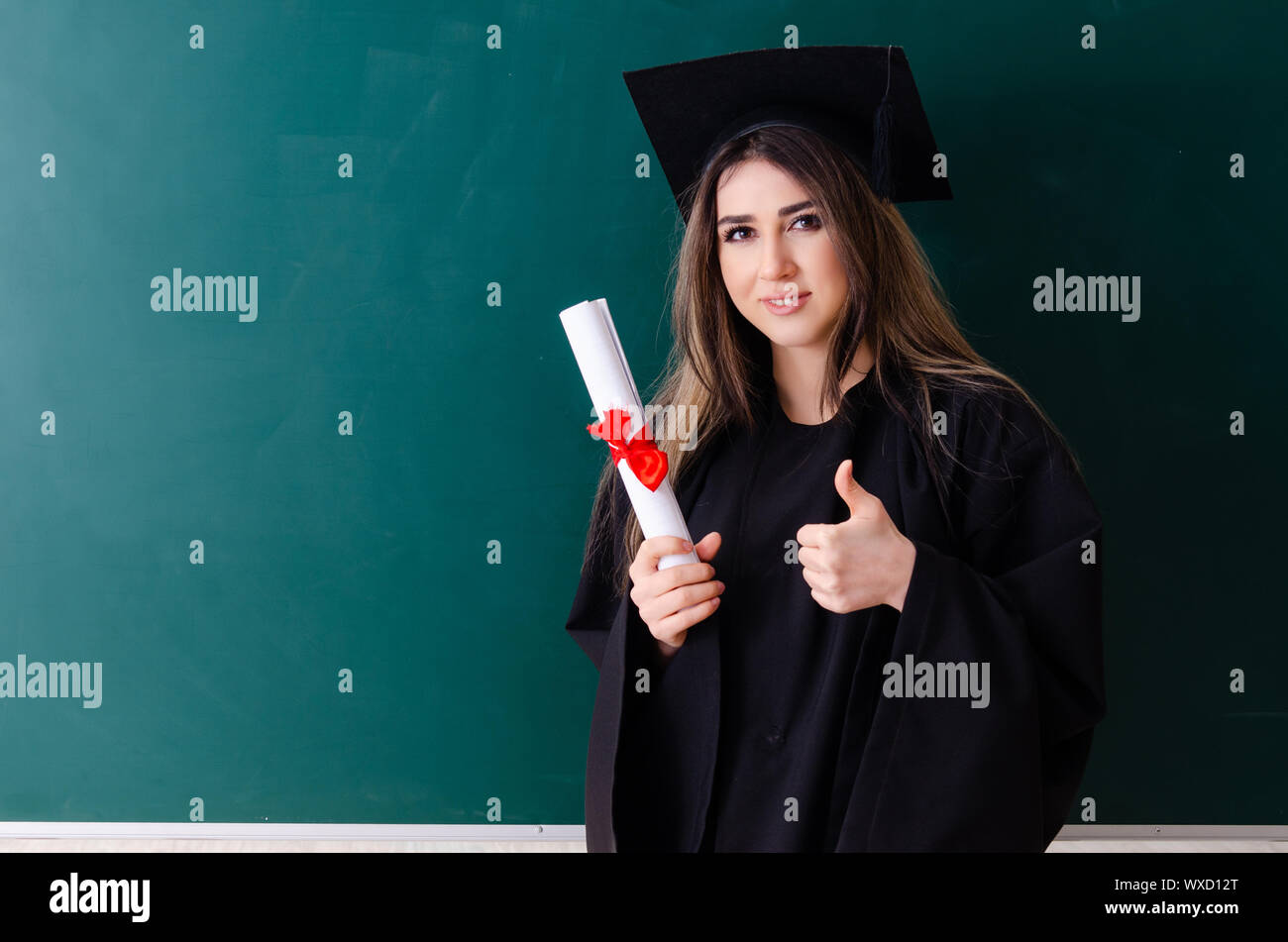 Female graduate student in front of green board Stock Photo - Alamy