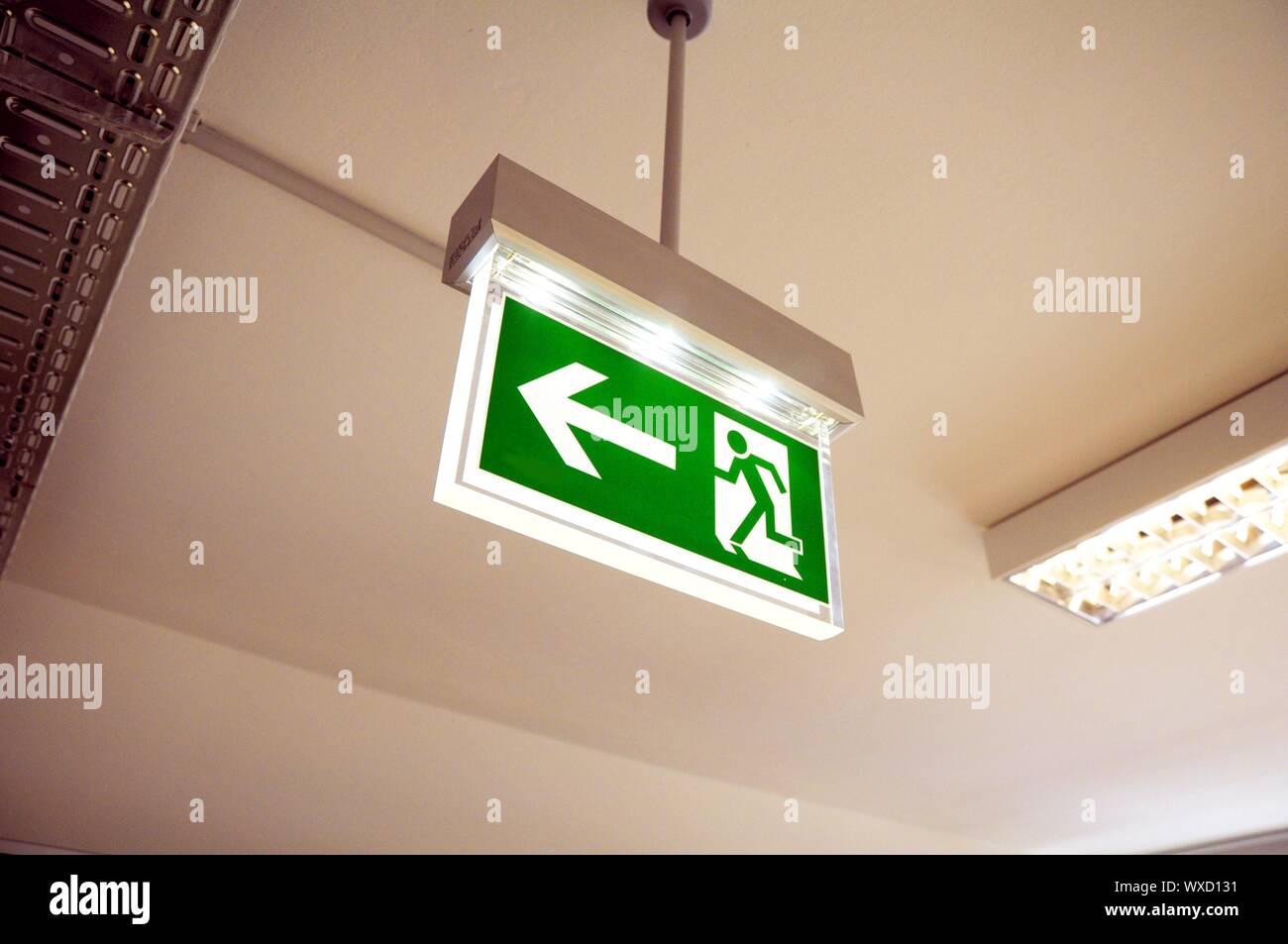 green emergency exit sign showing the way to escape Stock Photo - Alamy