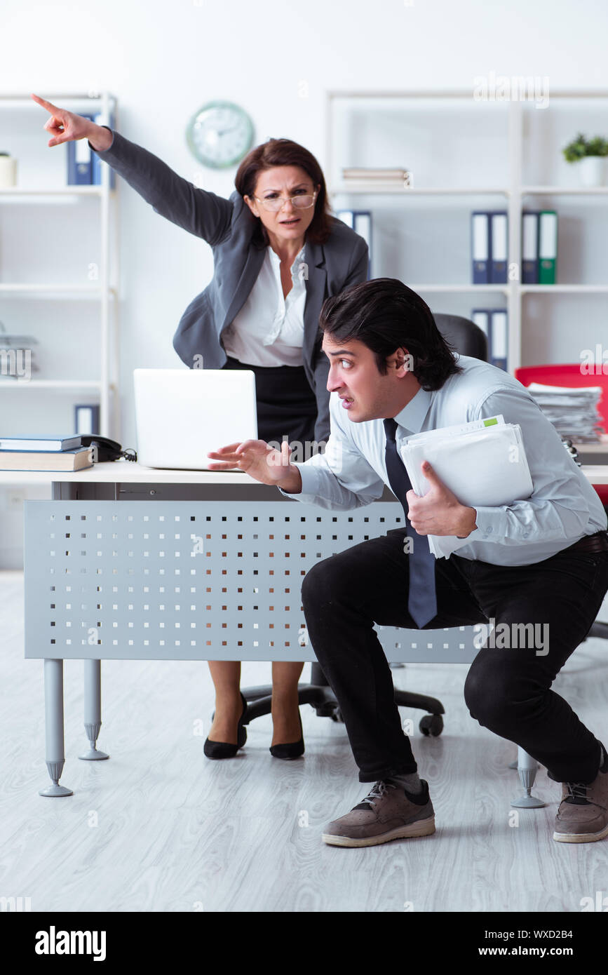 Old female boss and young male employee in the office Stock Photo - Alamy