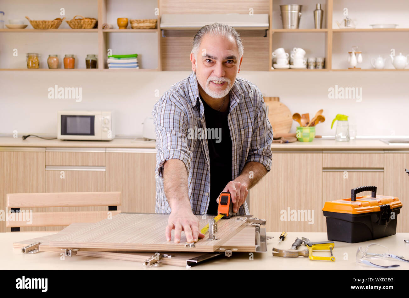 Aged contractor repairman working in the kitchen Stock Photo - Alamy
