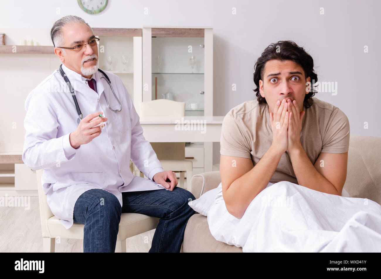 Old male doctor visiting young male patient Stock Photo - Alamy
