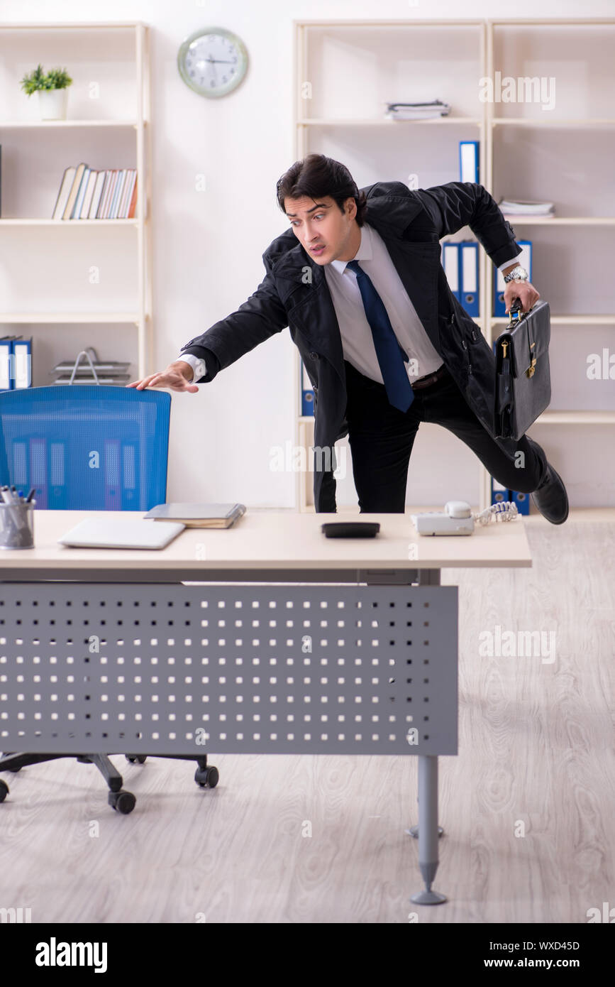 Young male employee in the office in time management concept Stock ...
