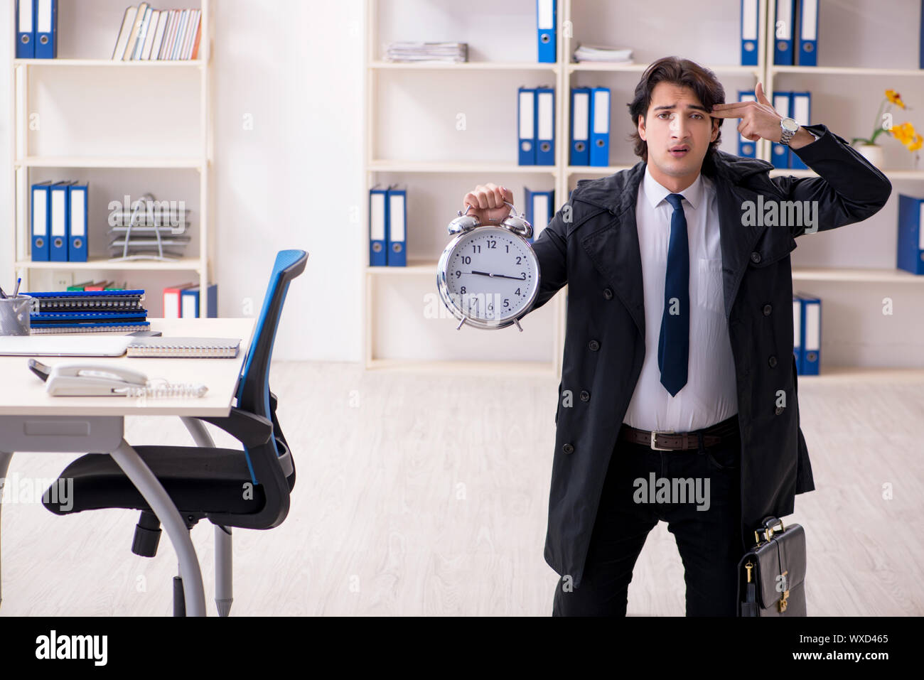 Young male employee in the office in time management concept Stock ...
