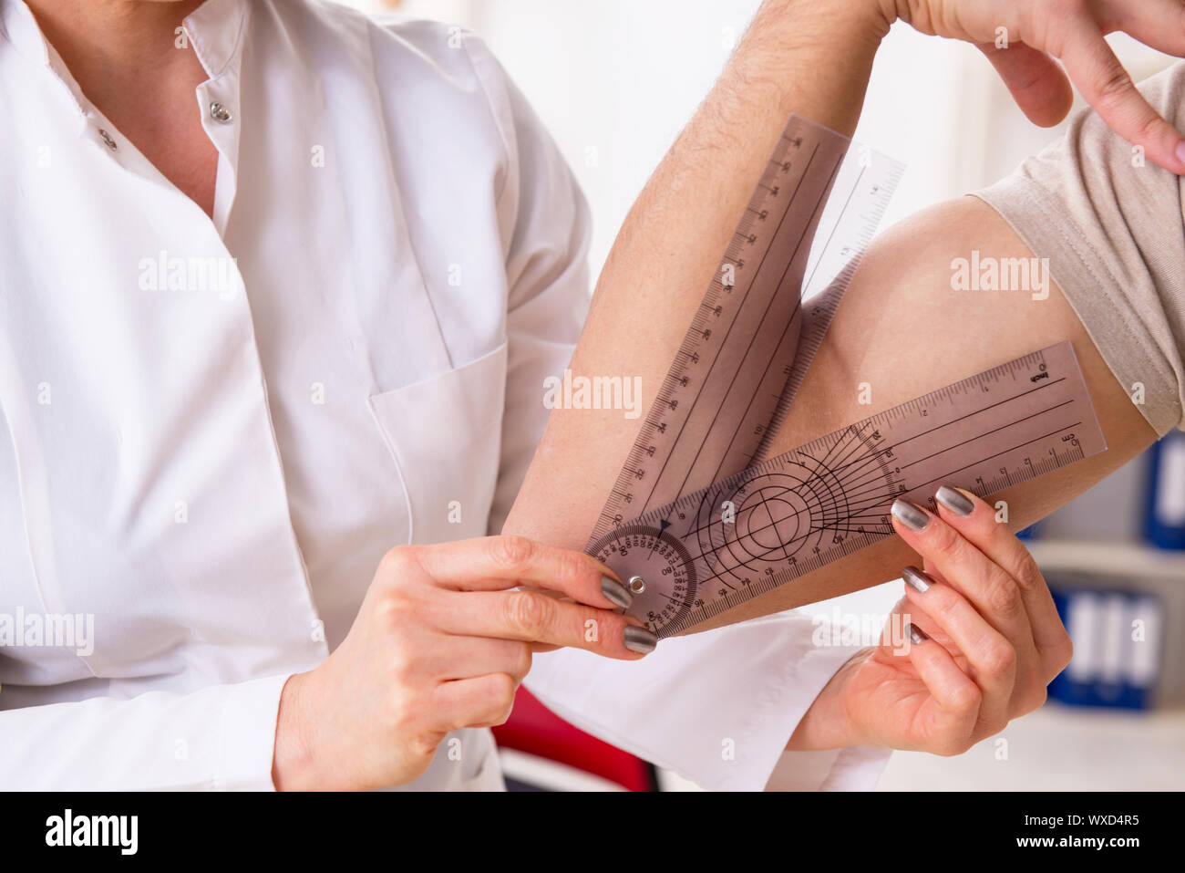 Female doctor checking patient's joint flexibility with goniometer ...