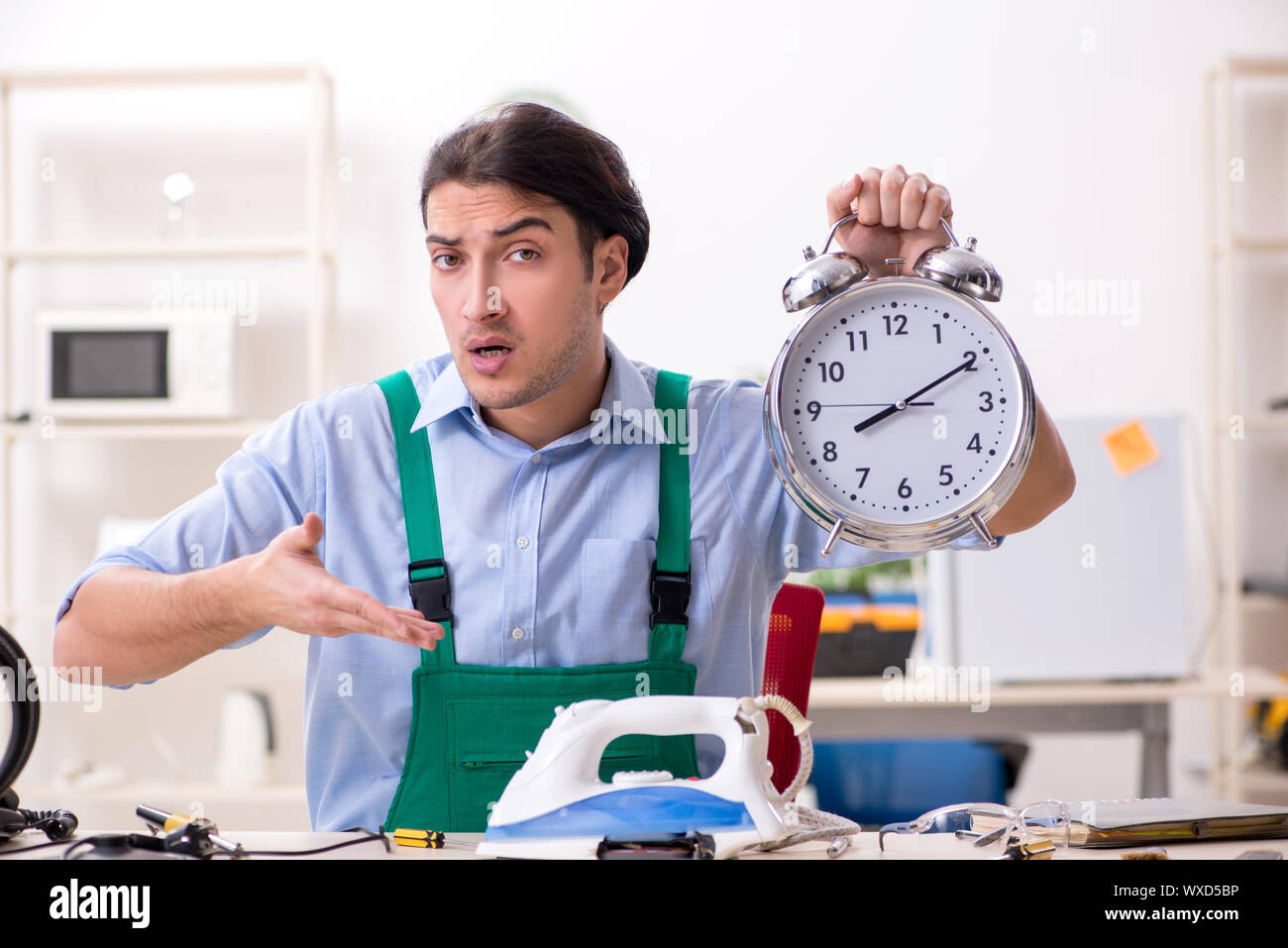 Young man repairman in time mannagement concept Stock Photo - Alamy