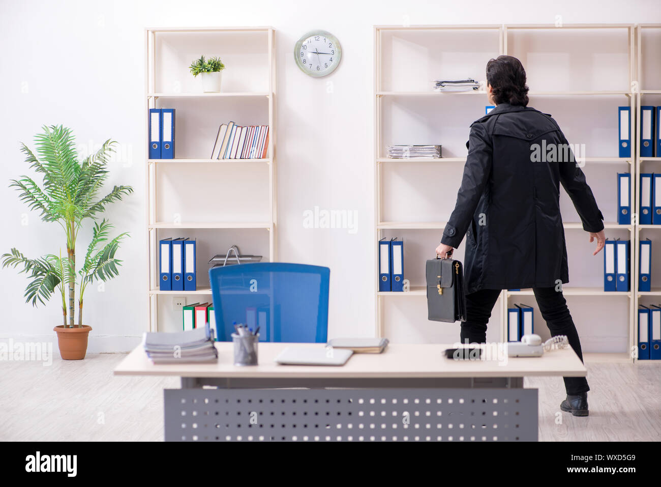 Young male employee in the office in time management concept Stock ...