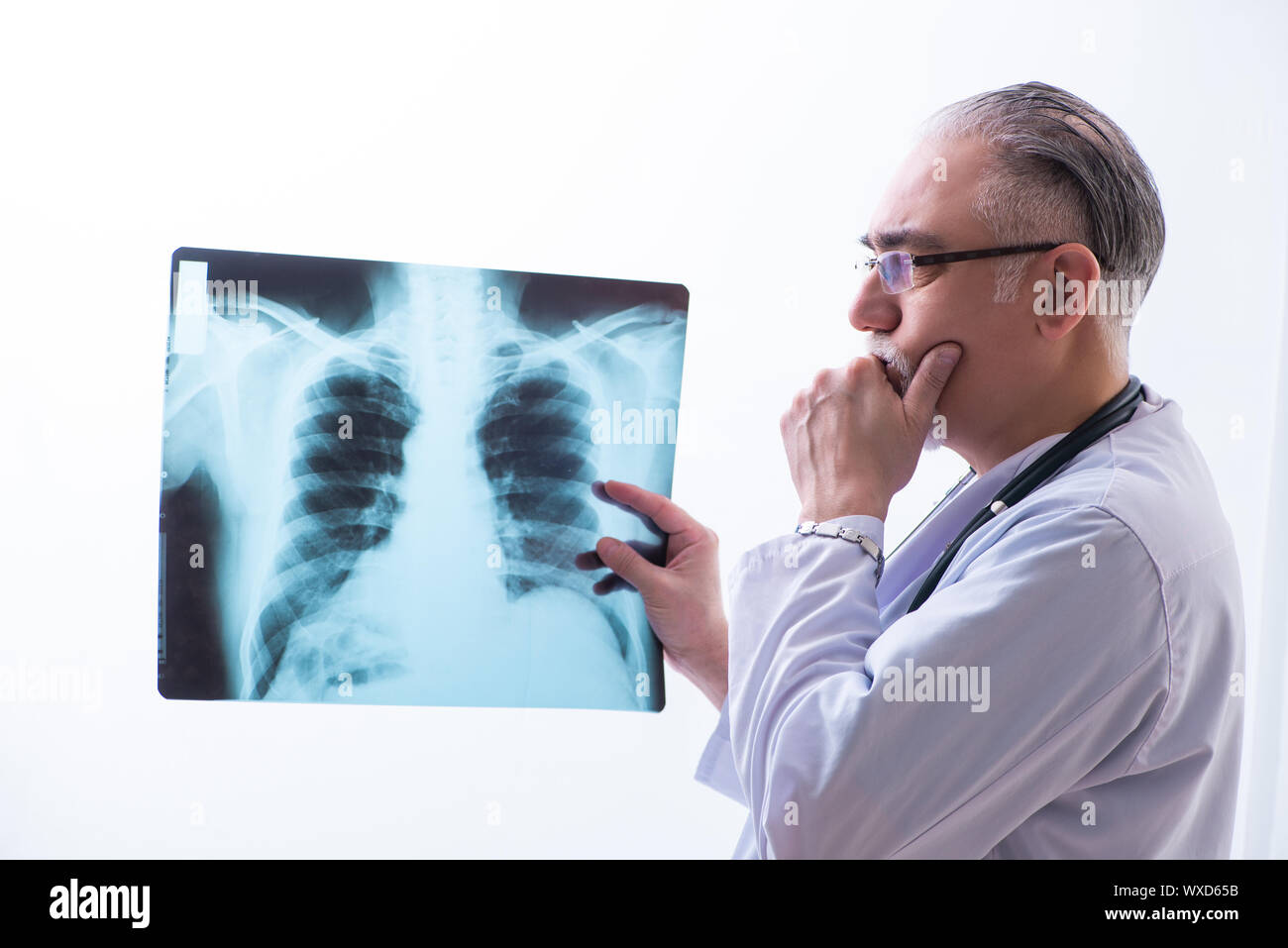 Old male doctor working in the clinic Stock Photo - Alamy