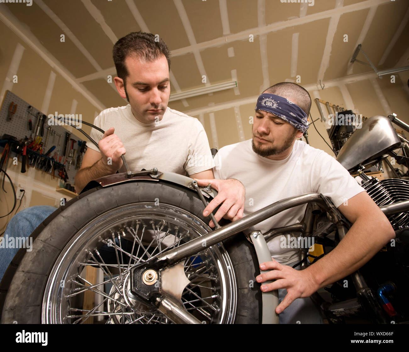 Two men working on a chopper-style motorcycle Stock Photo - Alamy