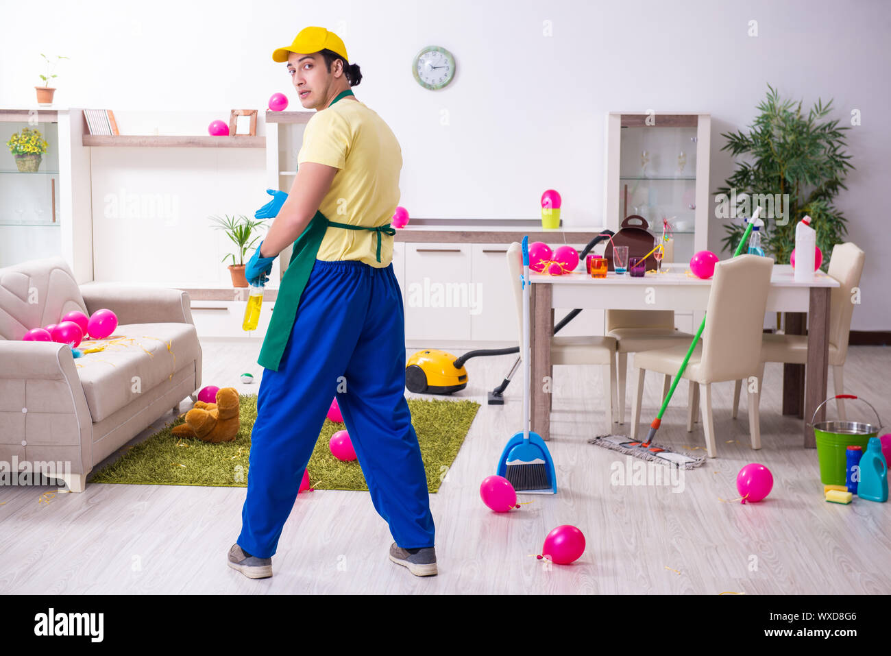 Young male contractor doing housework after party Stock Photo - Alamy