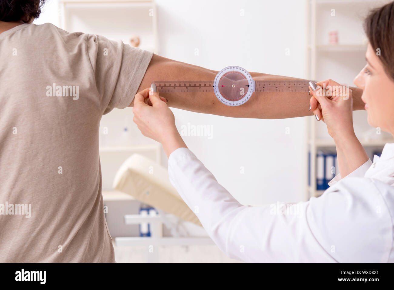 Female doctor checking patient's joint flexibility with goniometer ...
