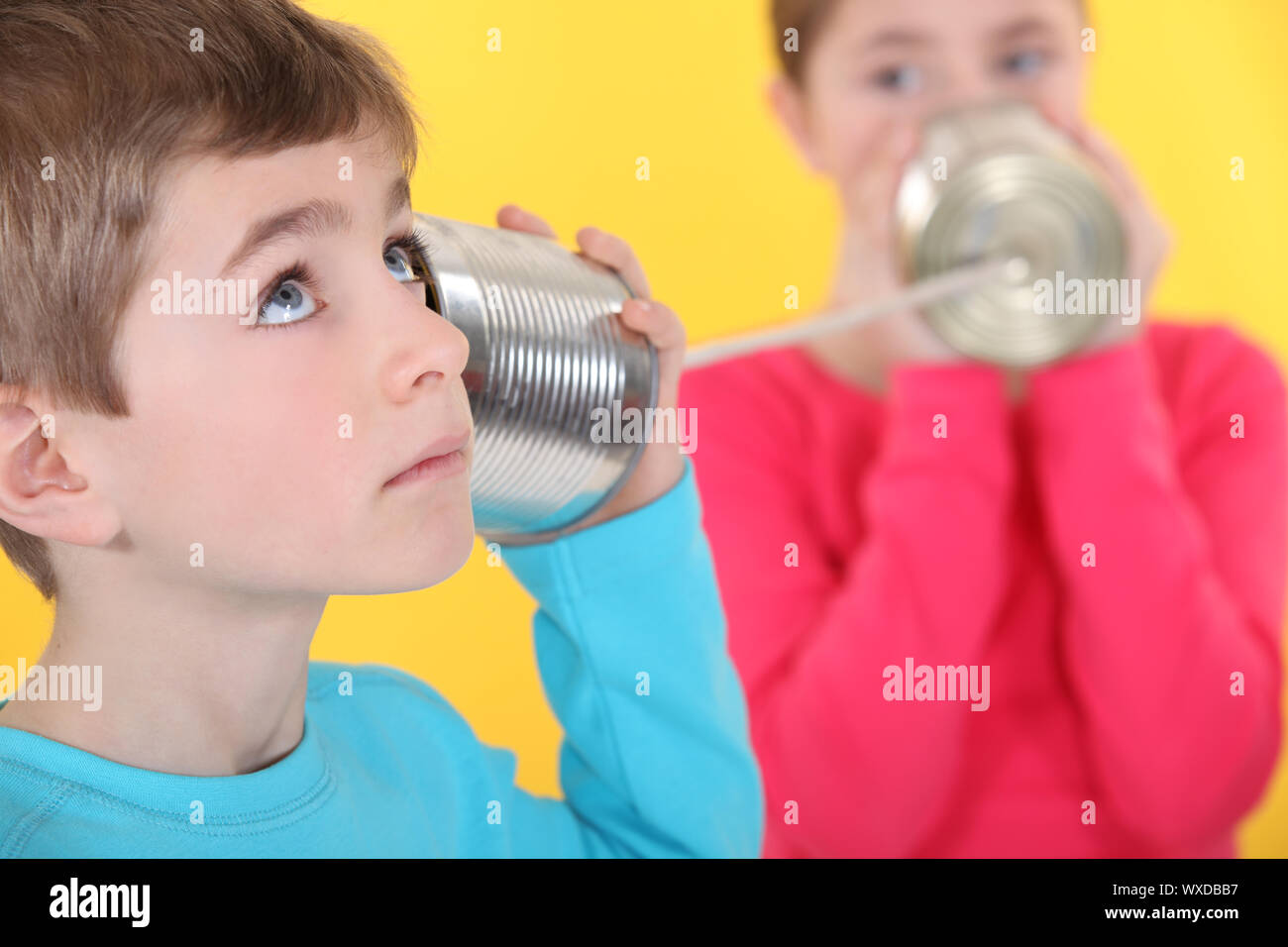 Two children communicating with tin can and string Stock Photo - Alamy