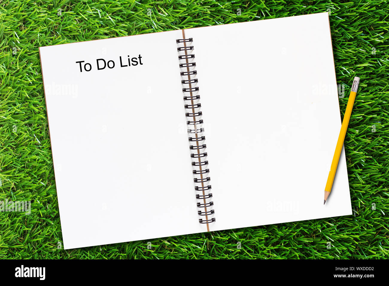 To do list concept, open notebook and yellow pencil on green grass ...
