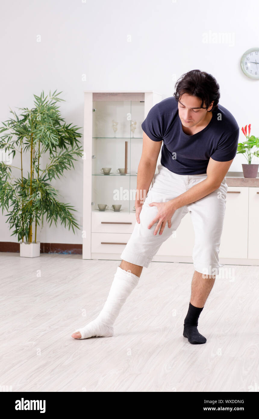 Leg injured young man suffering at home Stock Photo - Alamy