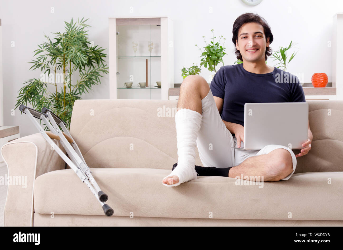 Leg injured young man suffering at home Stock Photo - Alamy