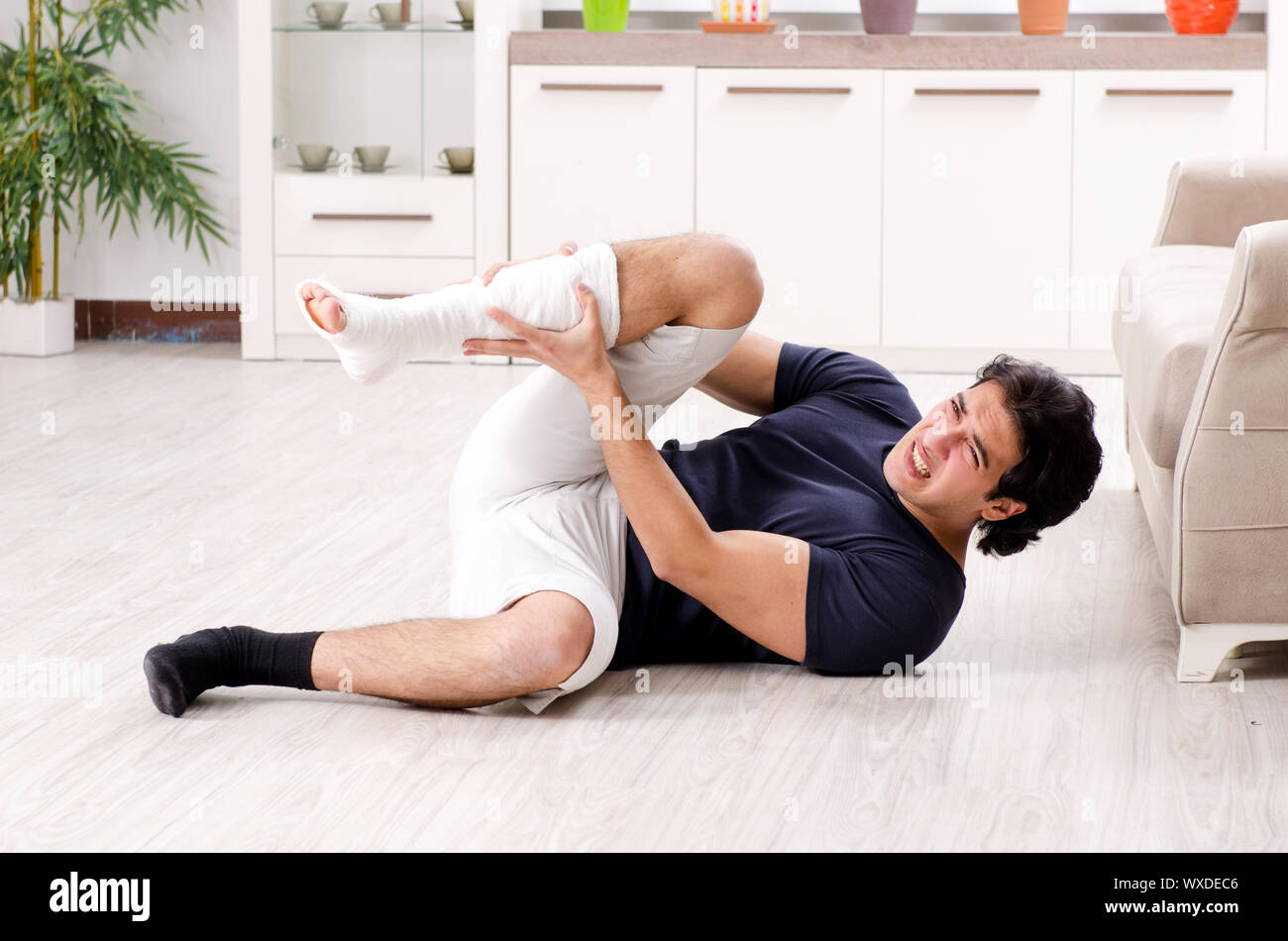 Leg injured young man suffering at home Stock Photo - Alamy