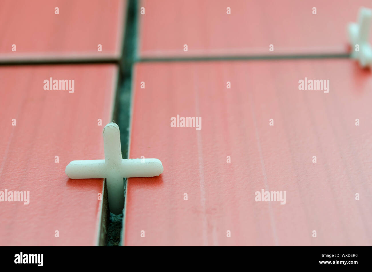 Closeup of tile spacer between red ceramic tiles Stock Photo - Alamy