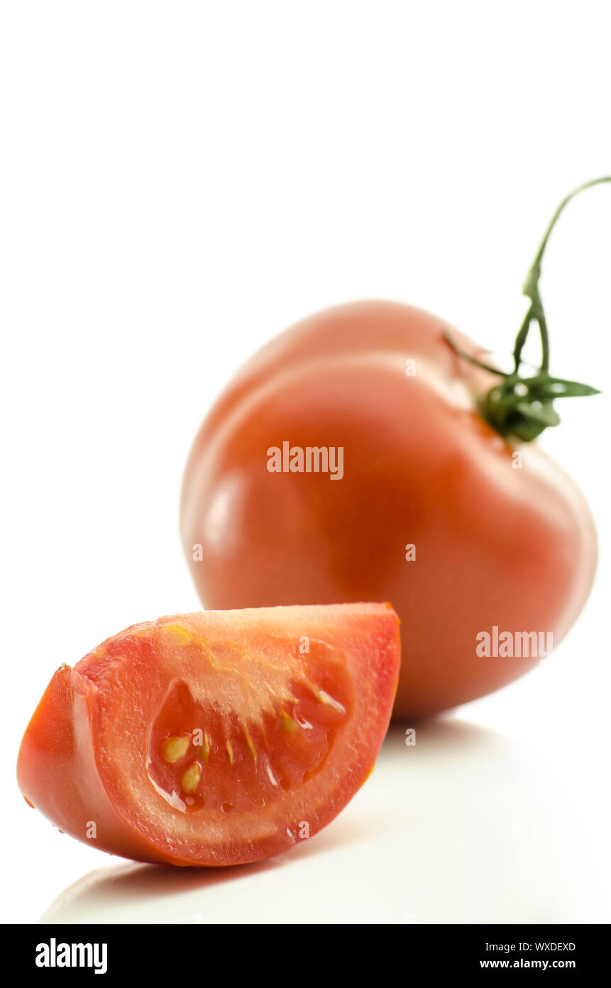 Ripe tomatoes with one cut in a quarter isolated on a white background ...