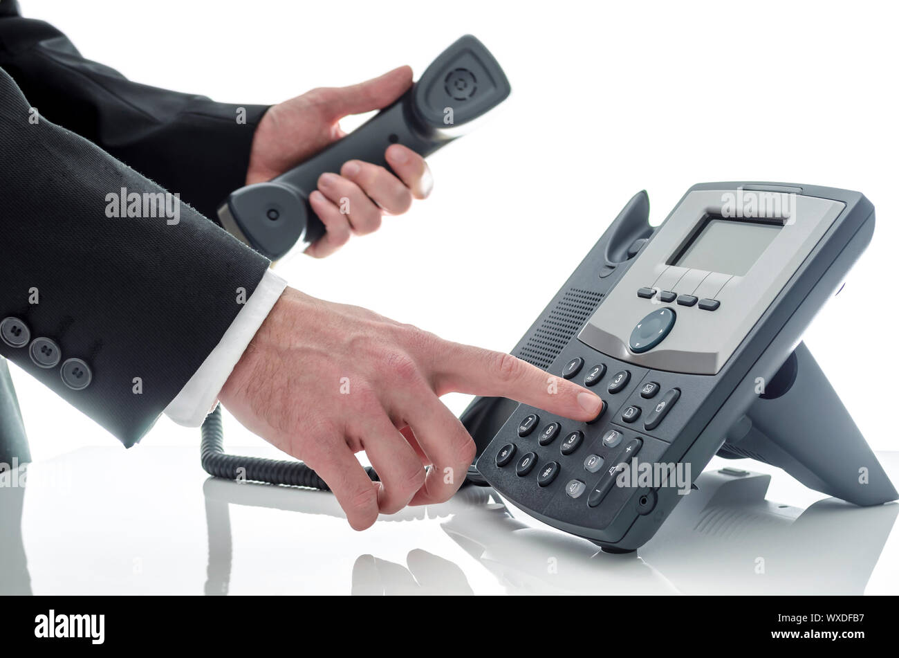 Male hand dialing number on a black phone against a white background ...