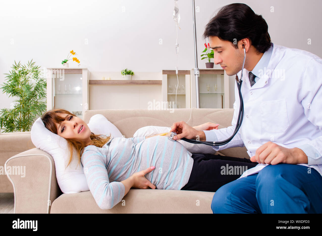 Young handsome doctor visiting pregnant woman at home Stock Photo - Alamy