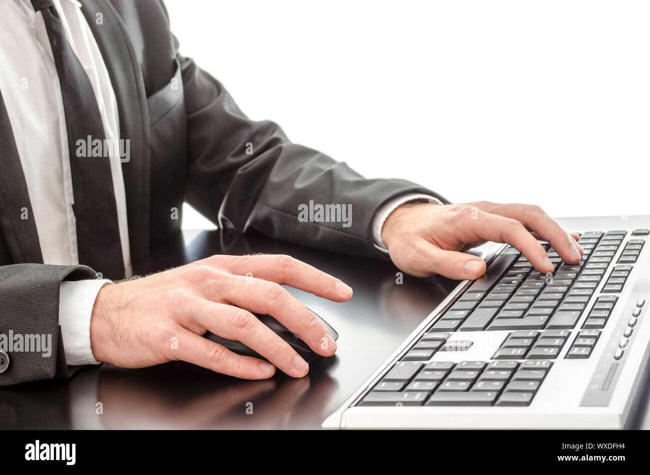 Closeup of a businessman's hands typing on keyboard on a black desk ...