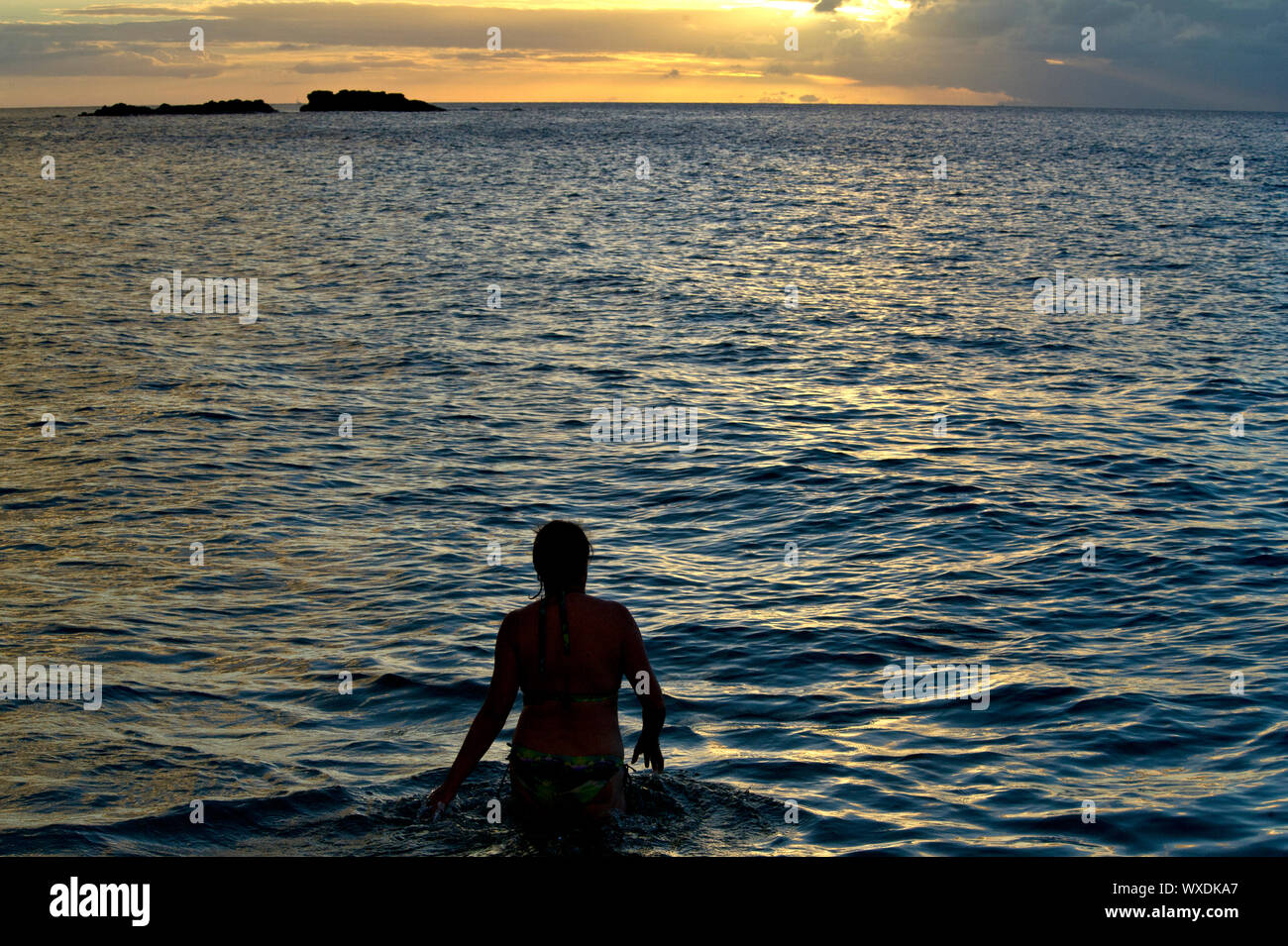 Woman going into the water at sunset at Waimea beach, Hawaii Stock ...