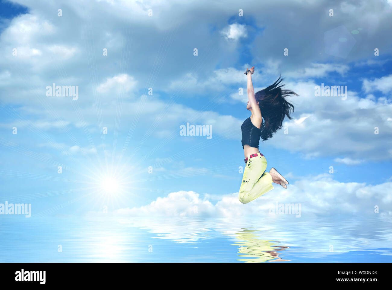 girl jumping against blue sky and sun with water reflection Stock Photo ...
