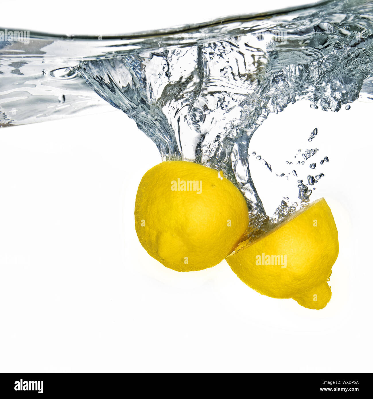 Fresh lemon dropped into water with bubbles isolated on white Stock ...