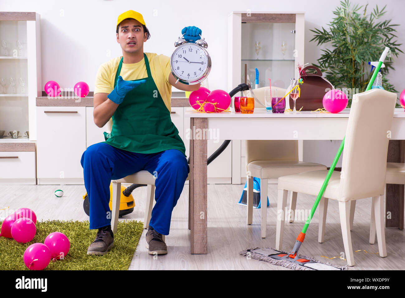 Young male contractor doing housework after party Stock Photo - Alamy