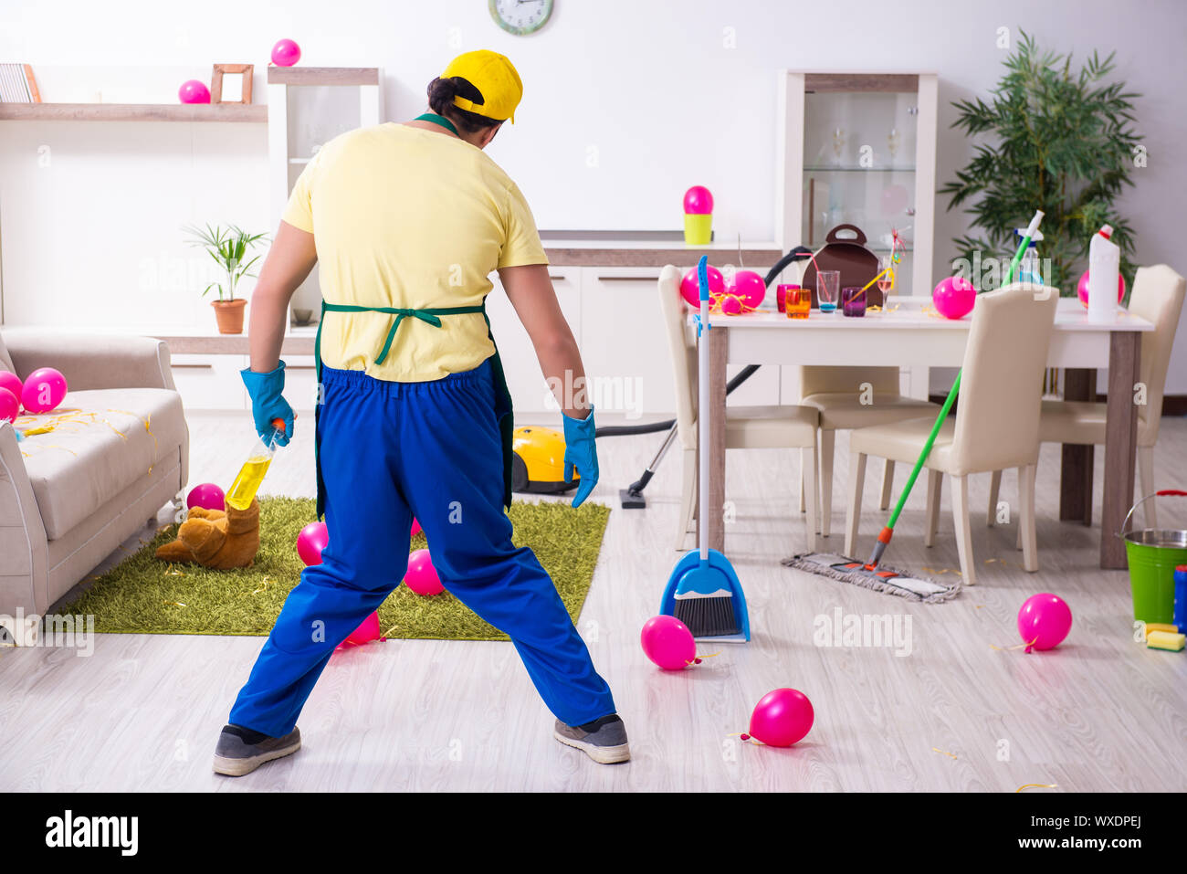 Young male contractor doing housework after party Stock Photo - Alamy