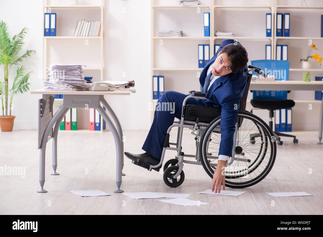 Young male employee in wheelchair working in the office Stock Photo - Alamy