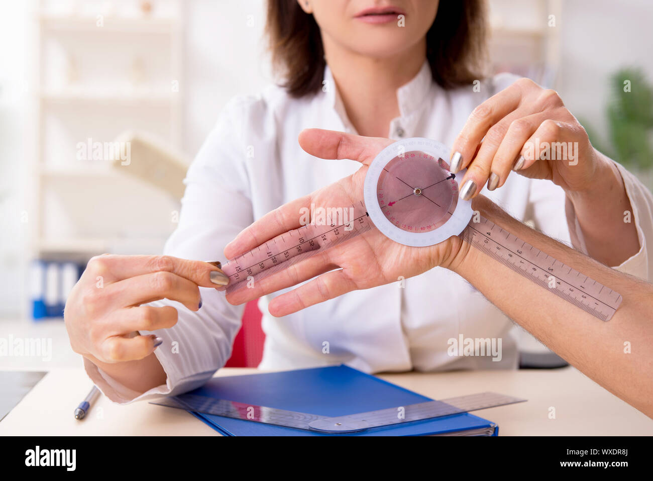 Female doctor checking patient's joint flexibility with goniometer ...