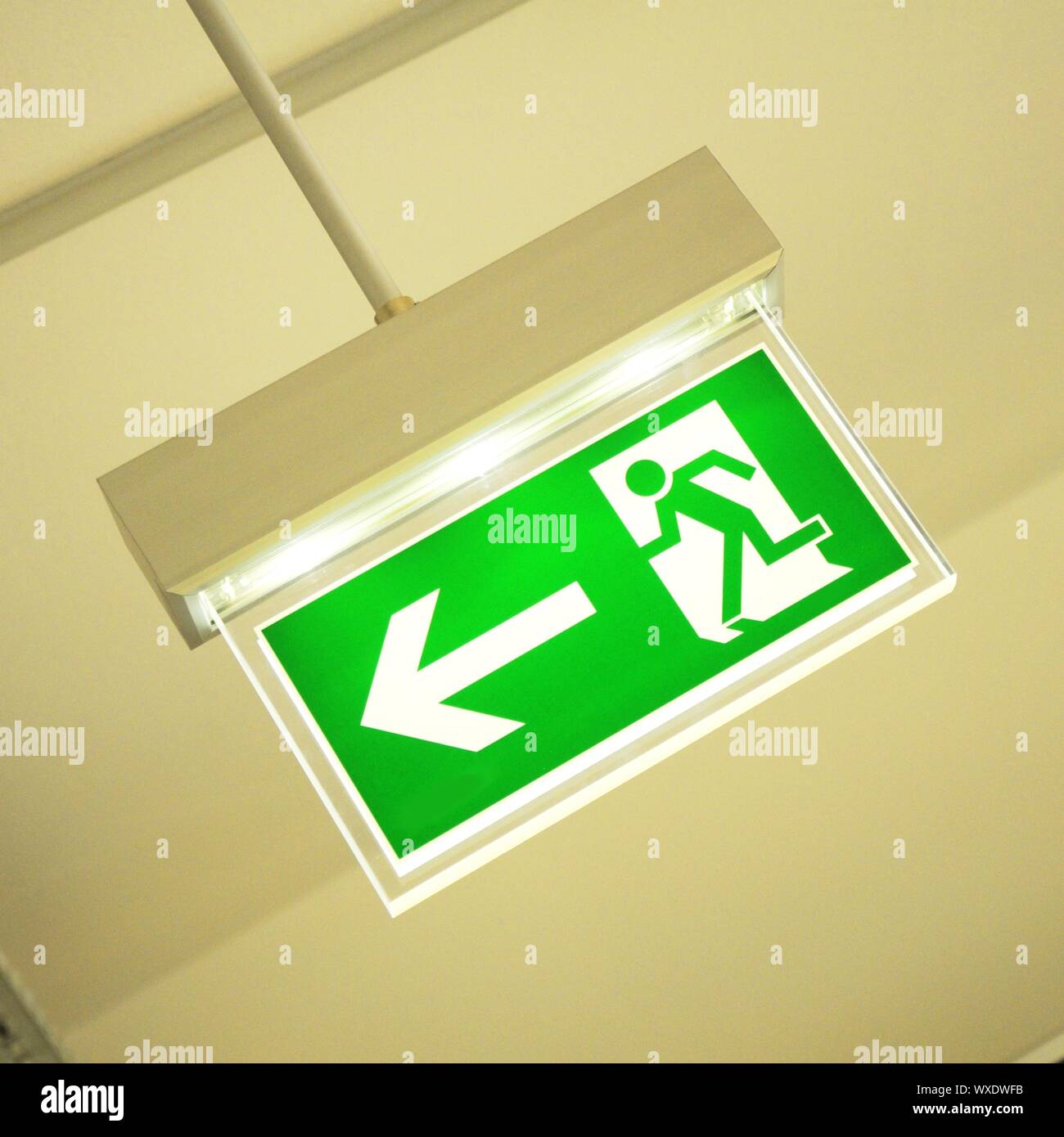 green emergency exit sign showing the way to escape Stock Photo - Alamy