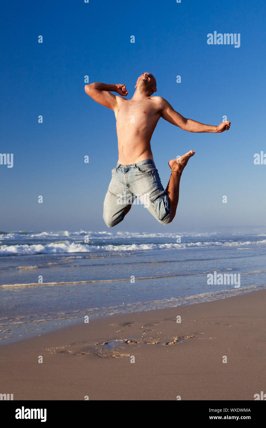 Young man jumping on the beach Stock Photo - Alamy