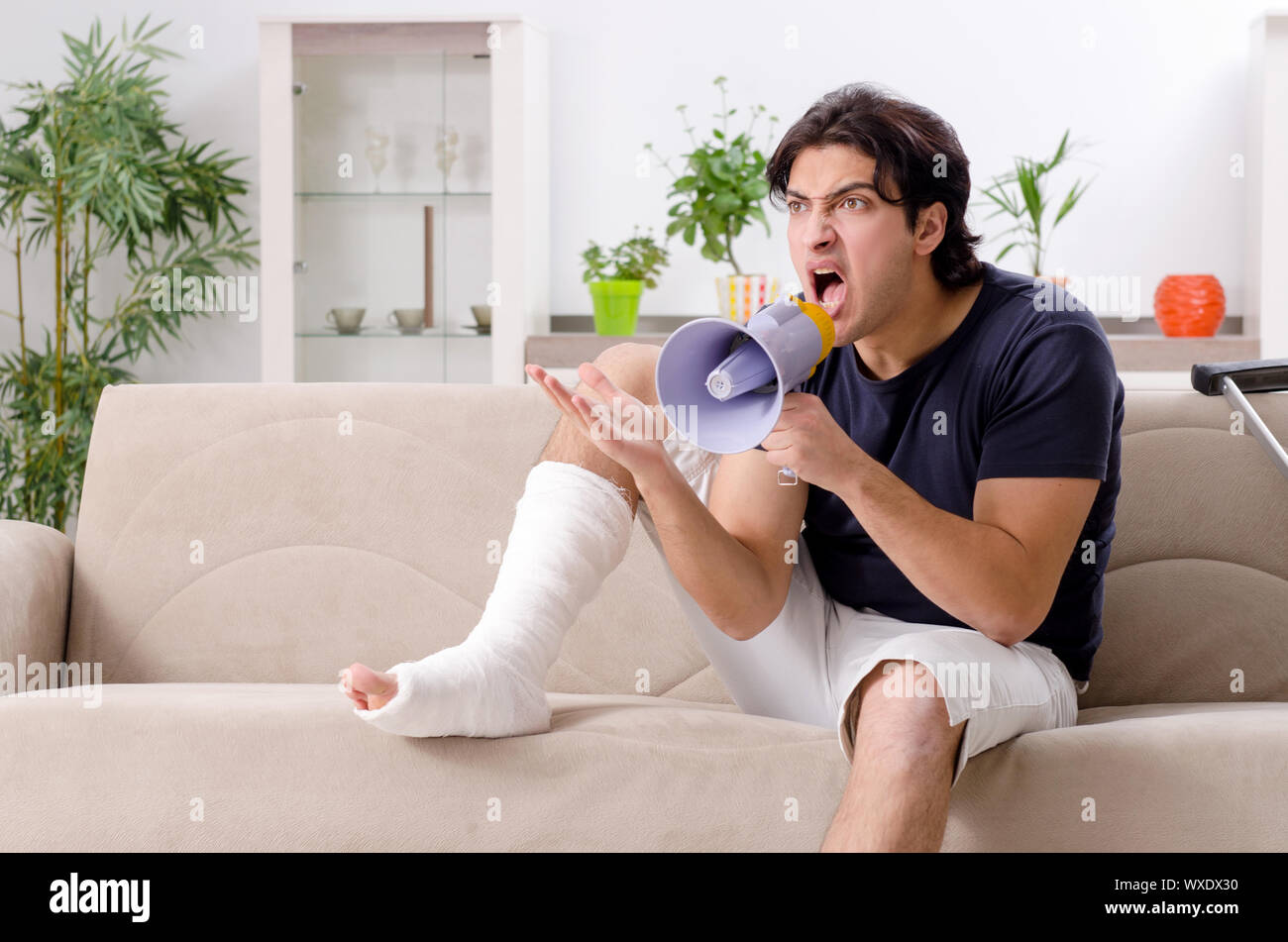 Leg injured young man suffering at home Stock Photo - Alamy