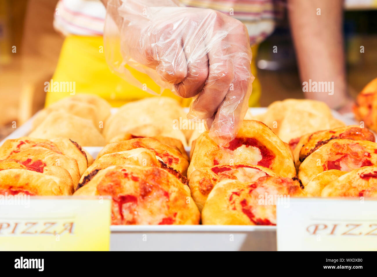 sales clerk in a supermarket picking up a slice of pizza Stock Photo ...